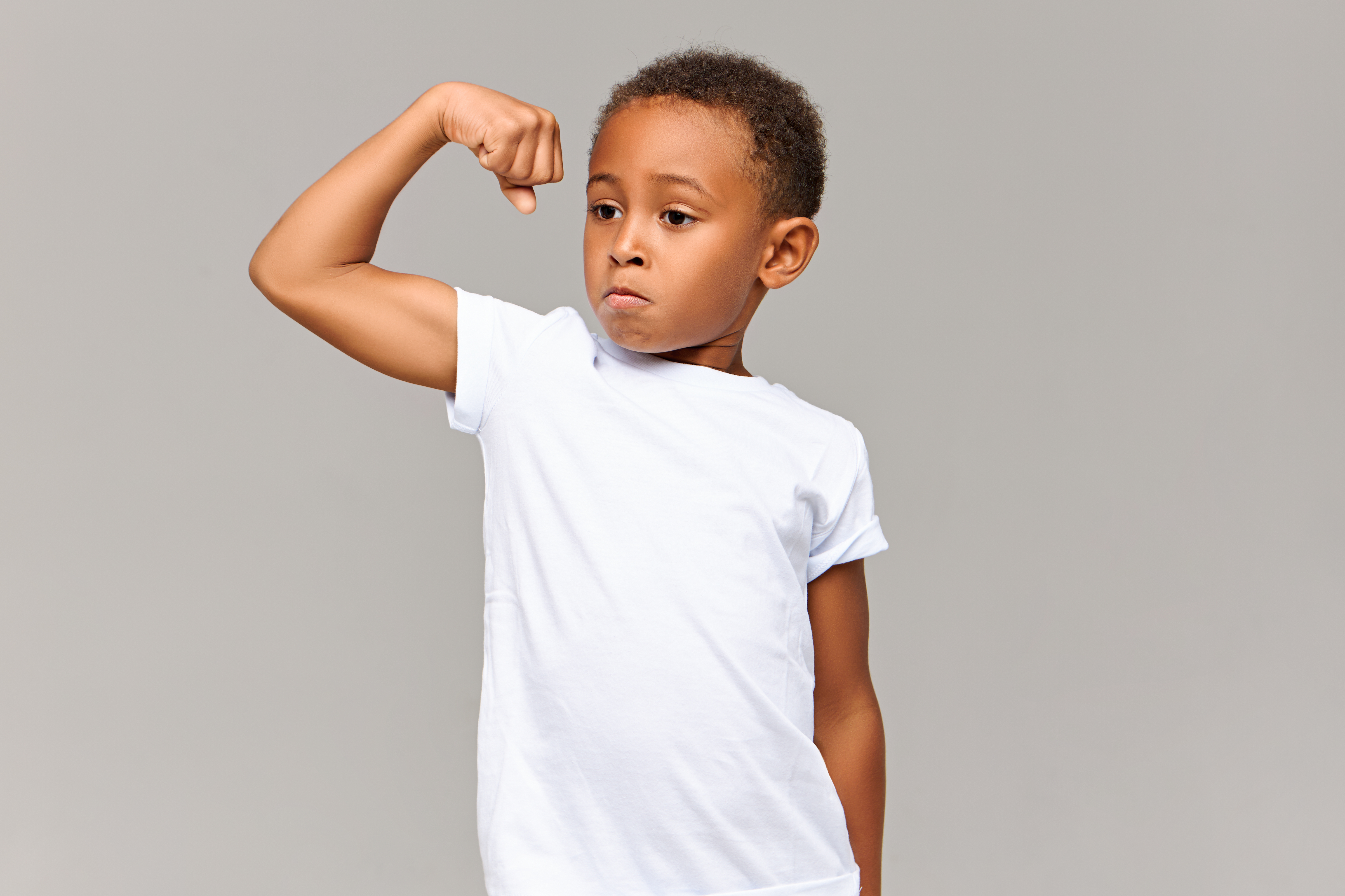 Cute dark skinned athletic male child with short Afro hairdo tensing ...